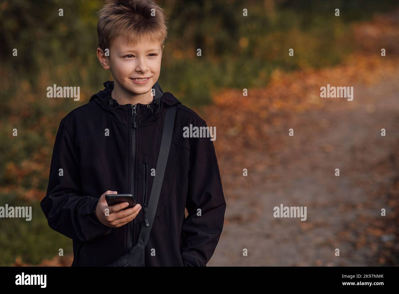 European appearance boy in a black jacket with tablet near school with ...