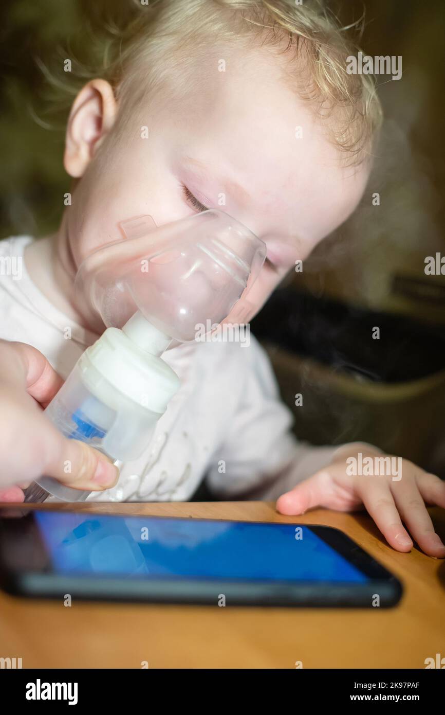 Cute little baby in mask of an inhaler. Procedure of inhalation at home ...