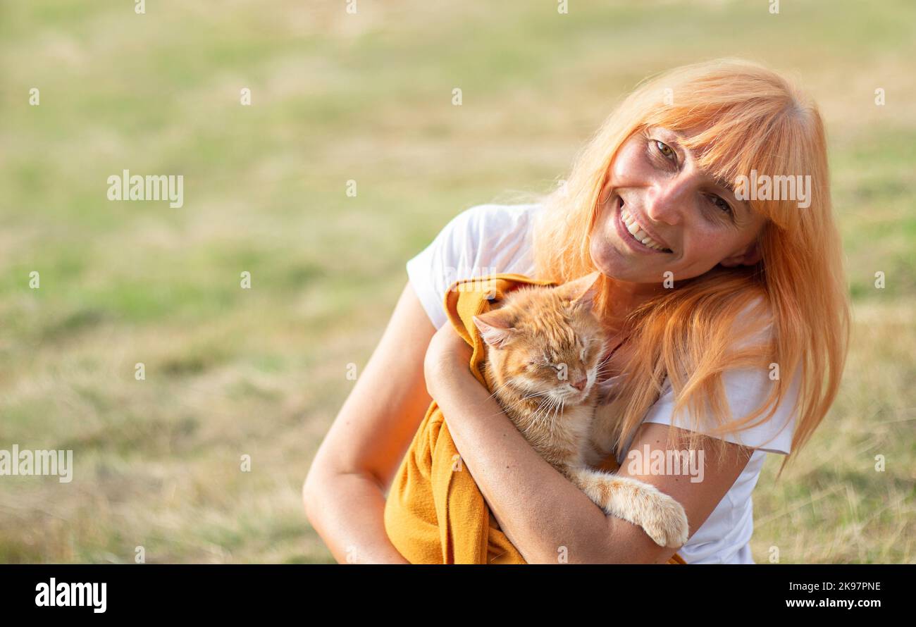 Beautiful cat with beautiful eyes. Ginger cat. A girl with red hair is ...