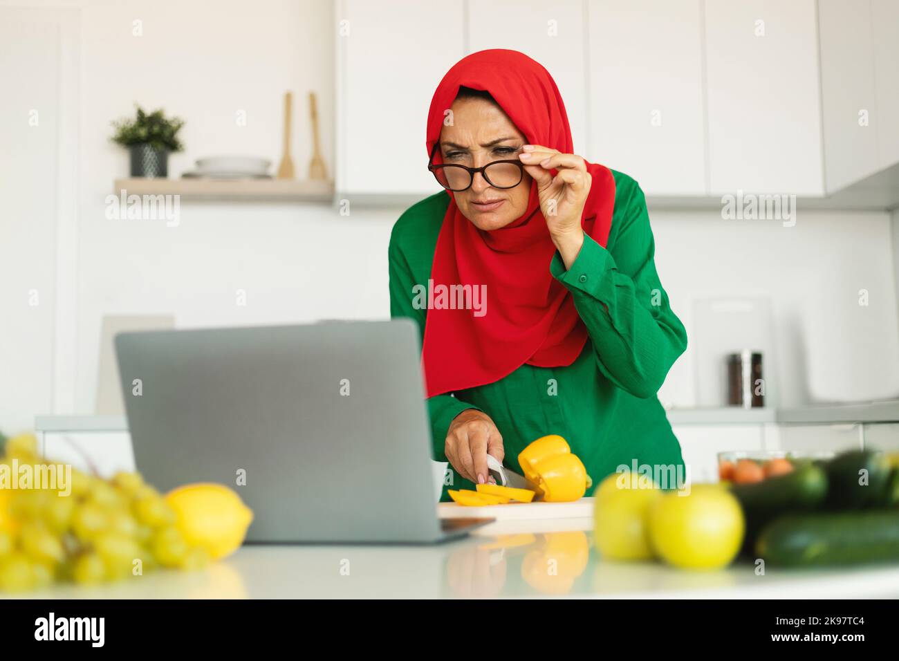 Muslim Lady Cooking Looking At Laptop Preparing Dinner In Kitchen Stock ...