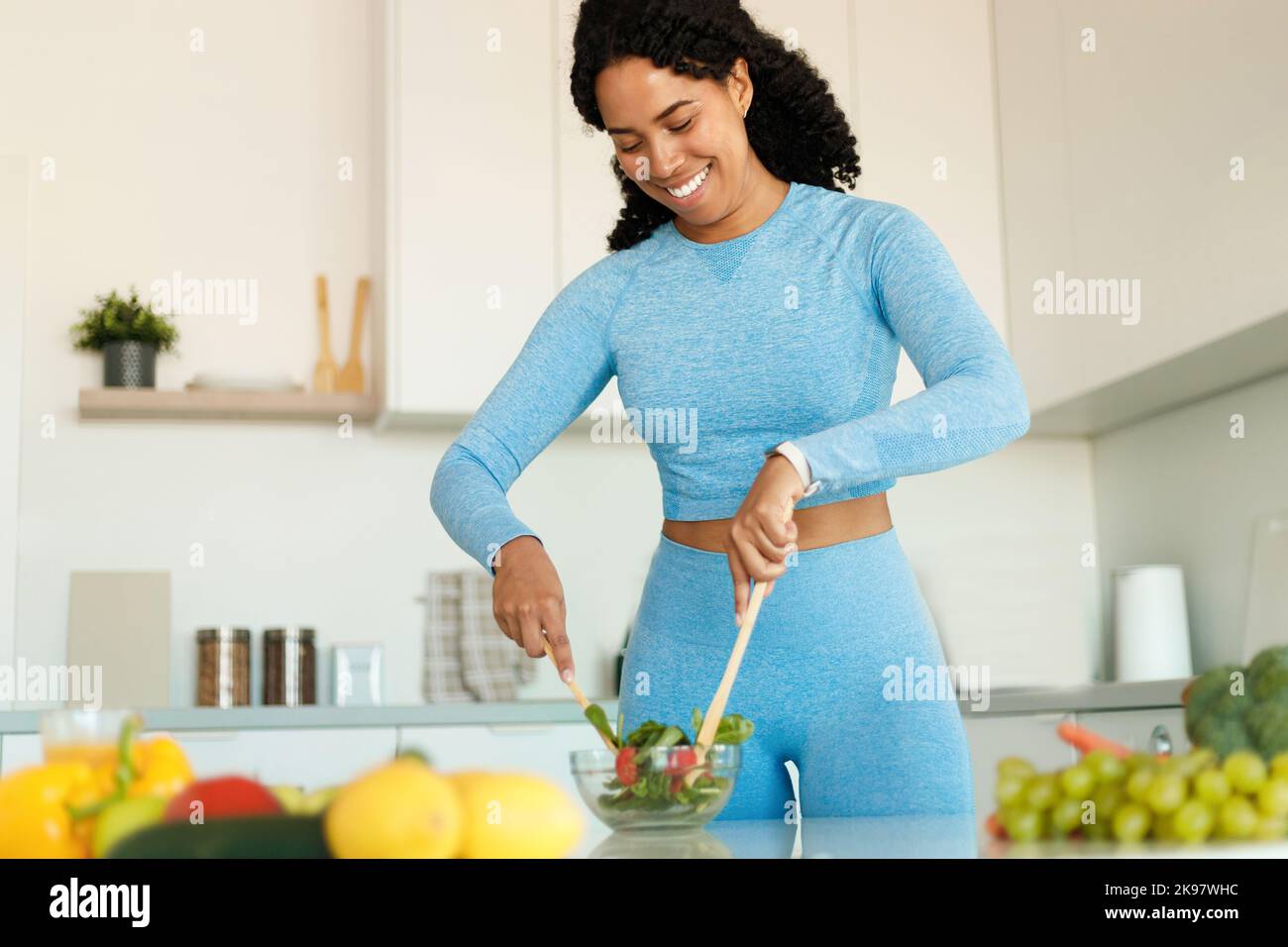 Healthy food. Happy fit black lady making salad, mixing fresh ...