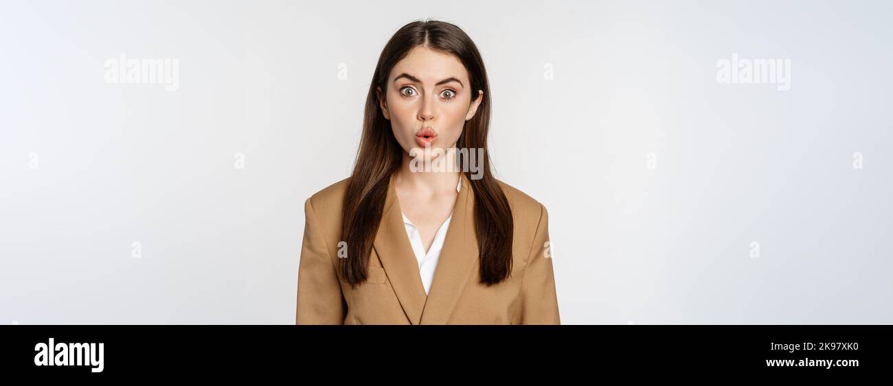 Portrait of office lady at workplace, looking surprised and curious ...