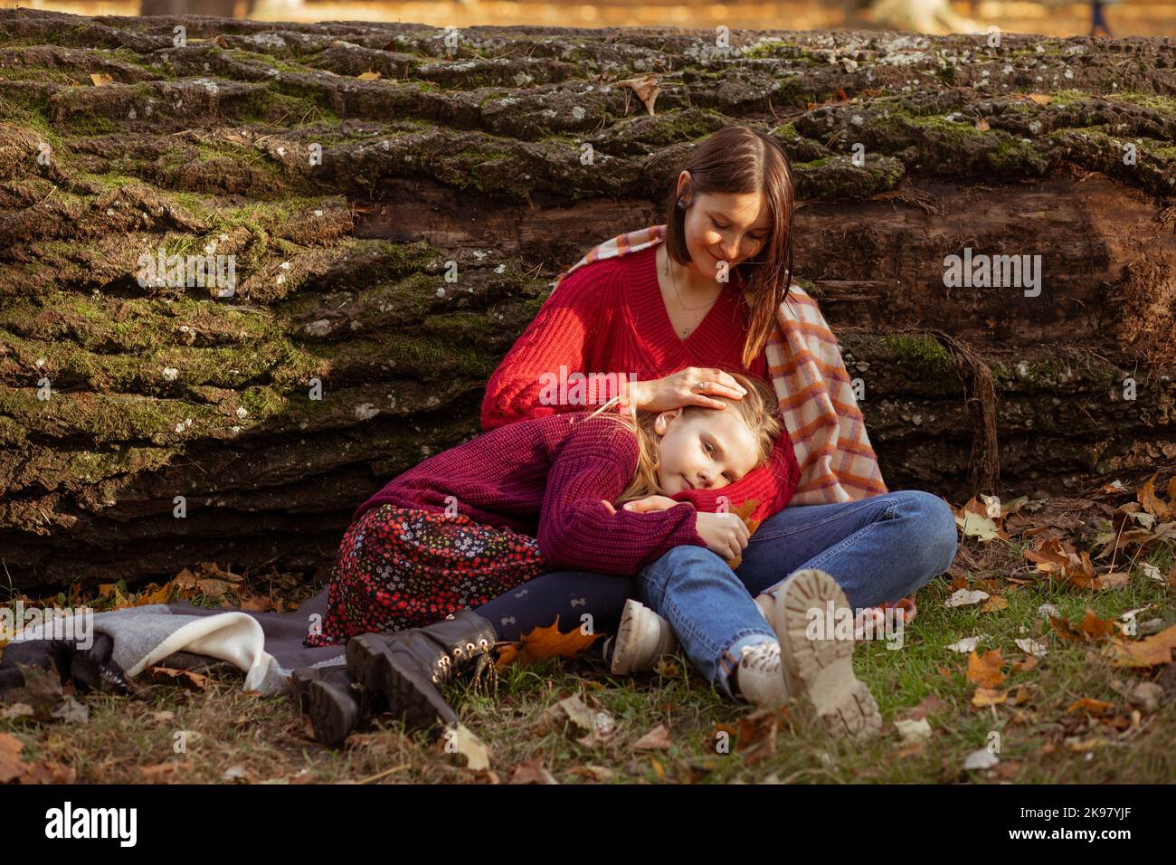Portrait of school aged girl lying on legs of loving mother in embraces ...