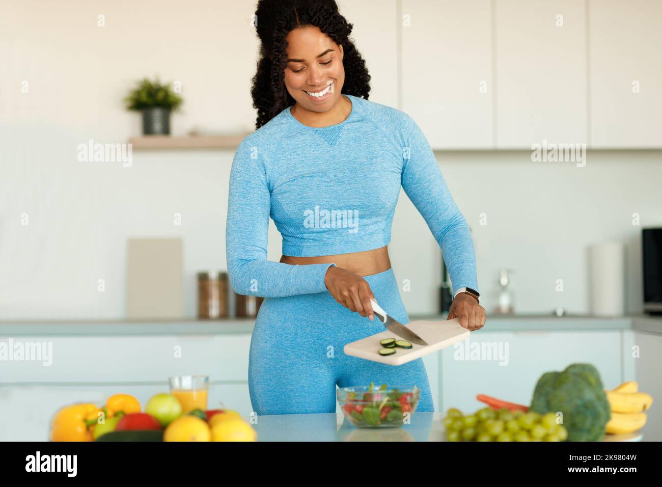Fit young african american woman preparing fresh salad, cooking fitness ...