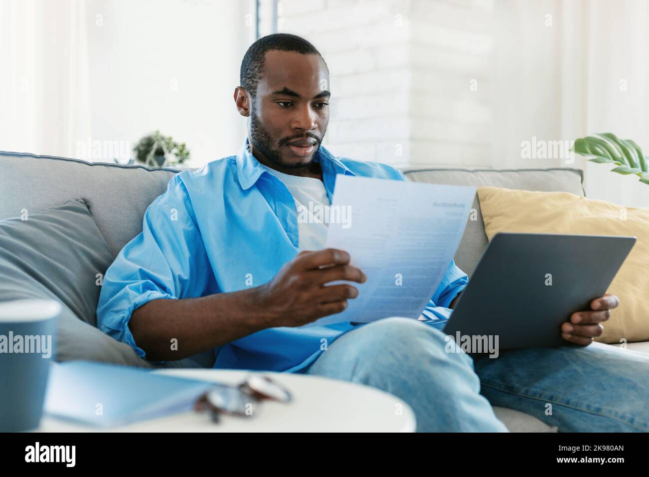 Paperwork concept. Portrait of black man working at home, reading paper ...
