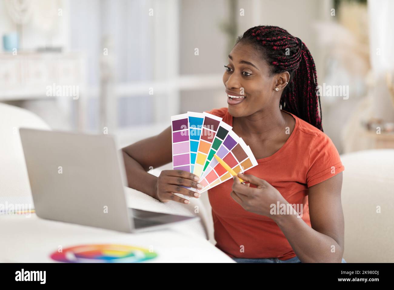 Black Female Interior Designer Using Laptop For Showing Swatches To ...