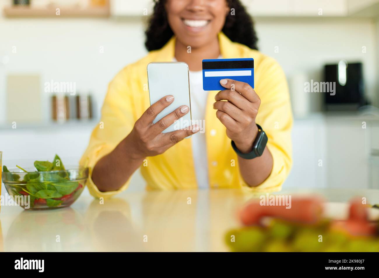 Young black woman buying food online, using cellphone and plastic ...