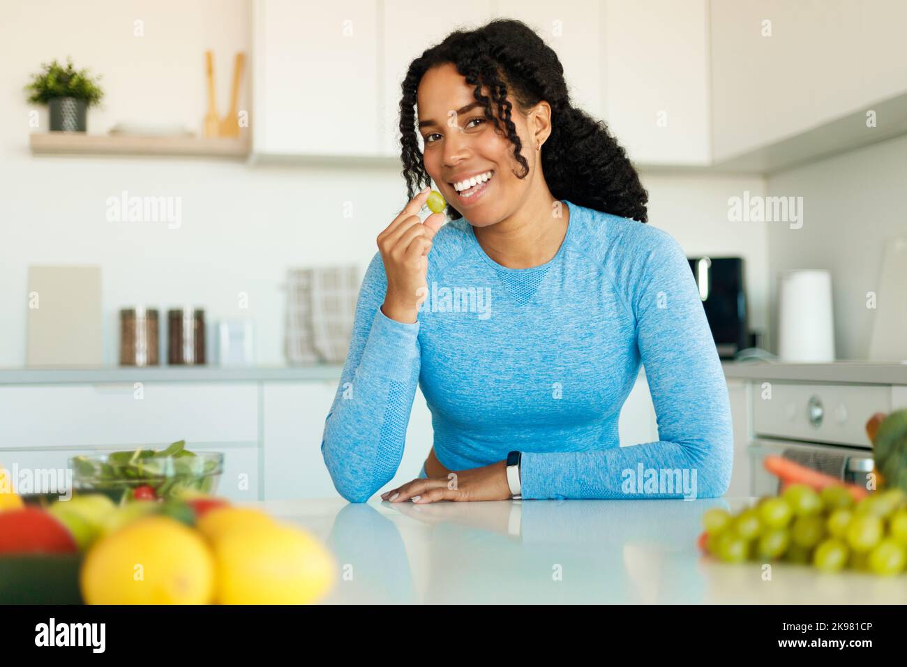 Positive fit african american woman in sportswear eating fruits for ...