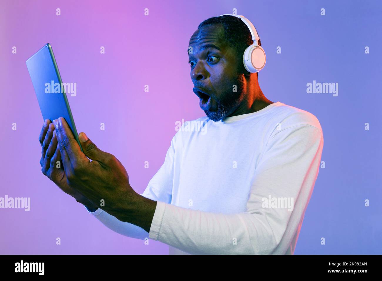 Emotional black man with wireless headset using digital tablet Stock ...