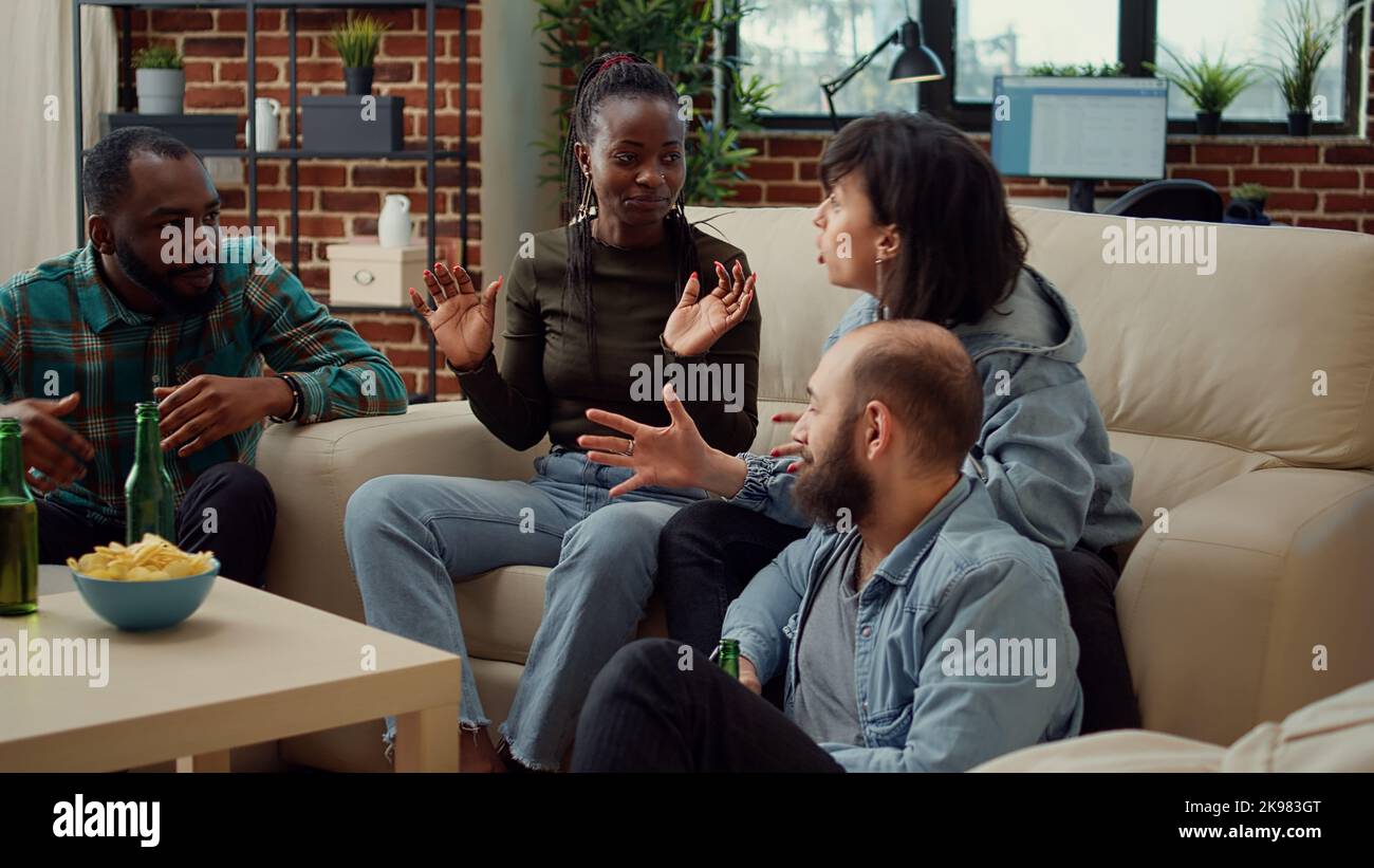 Group of friends enjoying funny conversation at house party, drinking ...