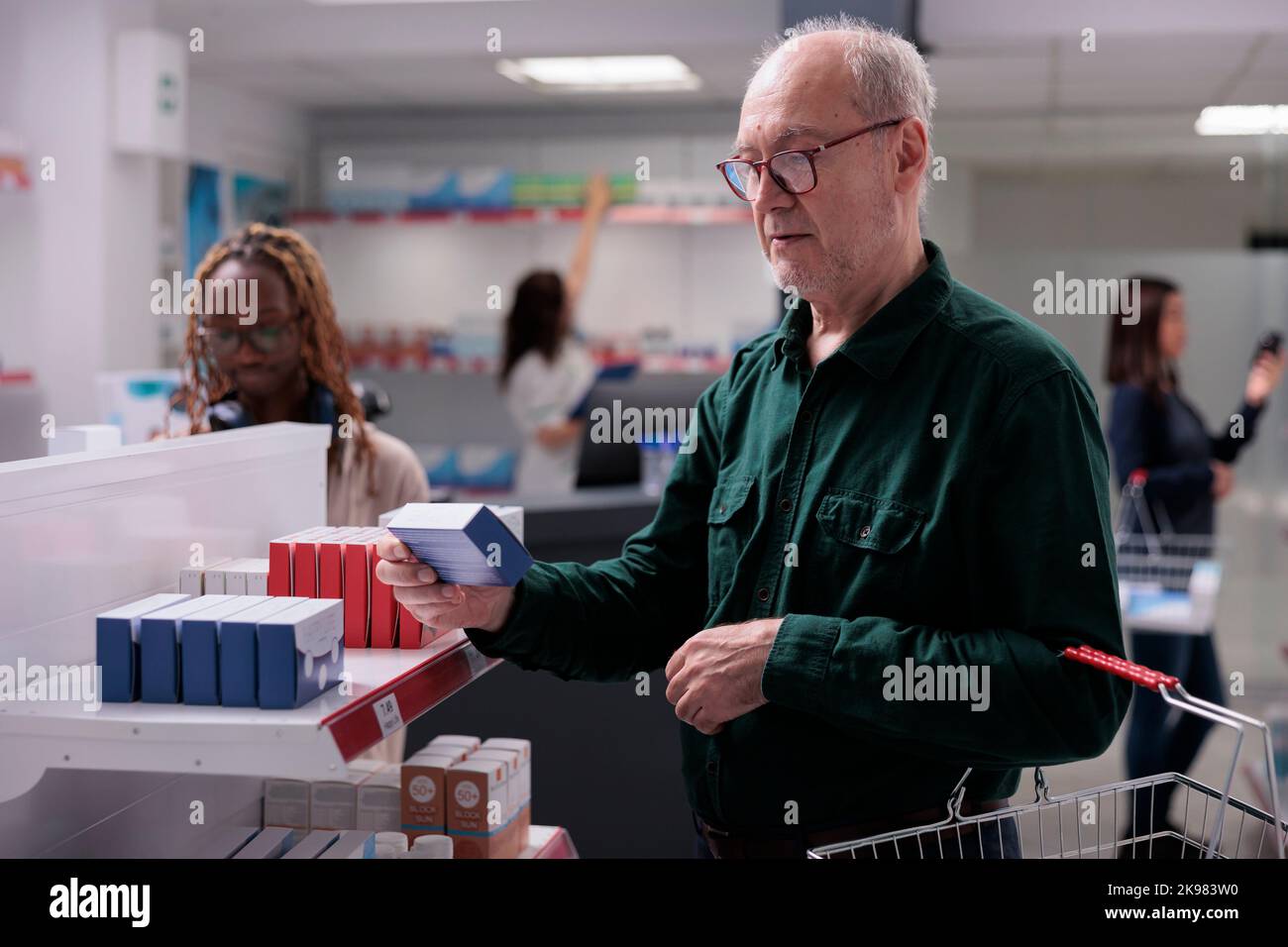Senior man client holding shop basket in pharmacy looking at drugs ...