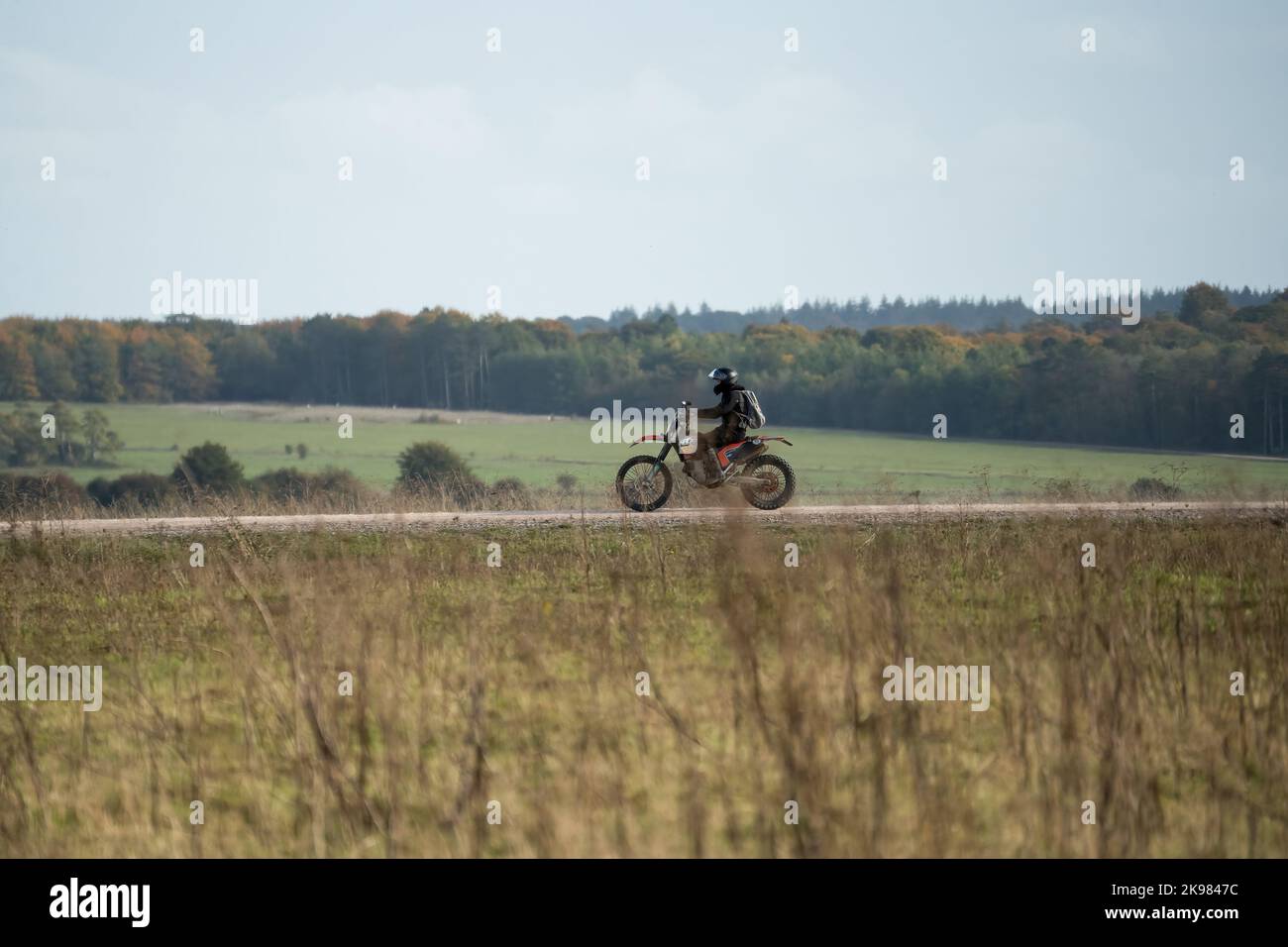 a motor cyclist (biker) riding their off-road motorbike along a dusty ...