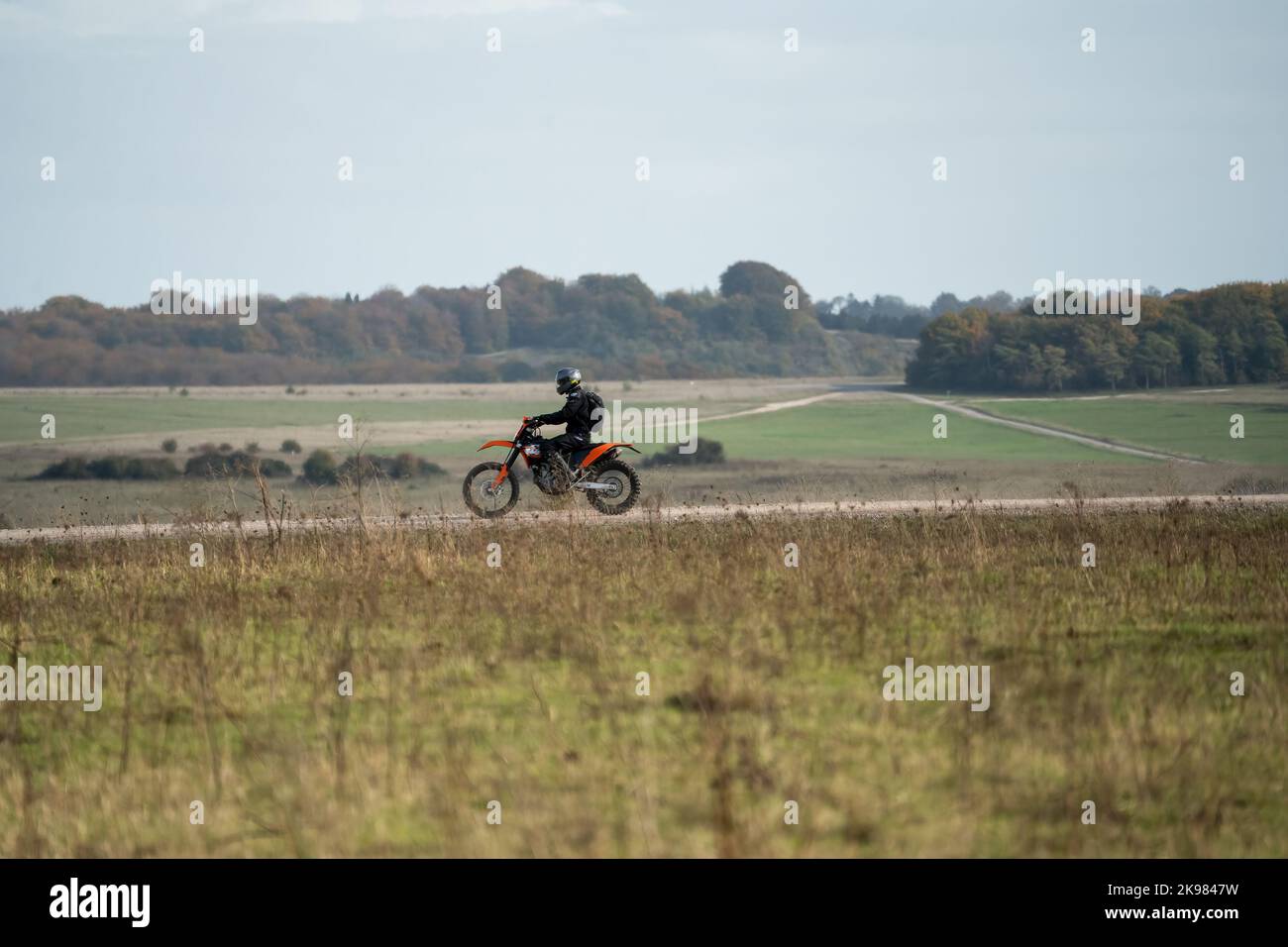 a motor cyclist (biker) riding their off-road motorbike along a dusty ...