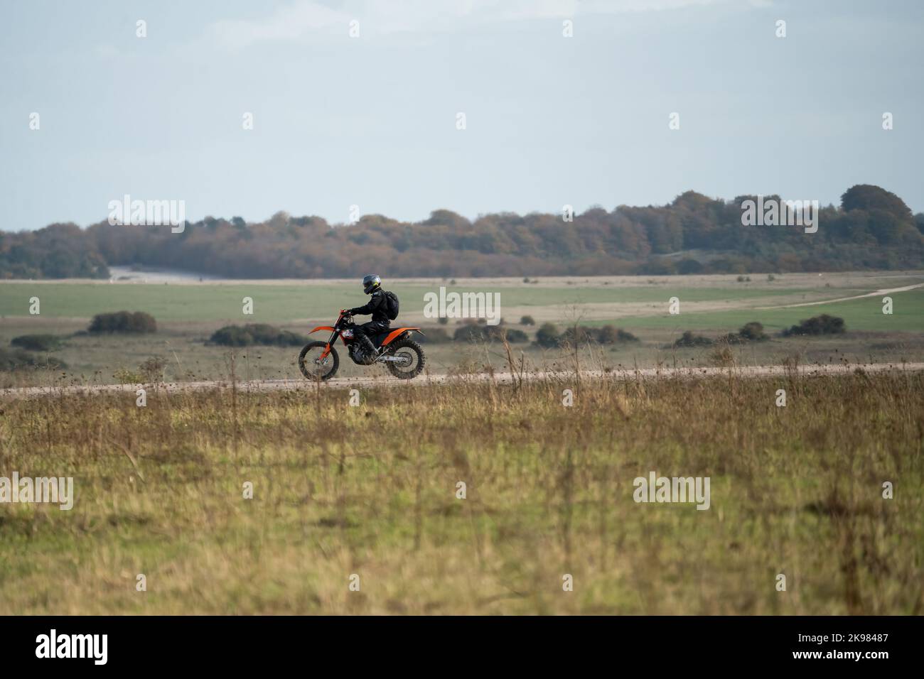 a motor cyclist (biker) riding their off-road motorbike along a dusty ...