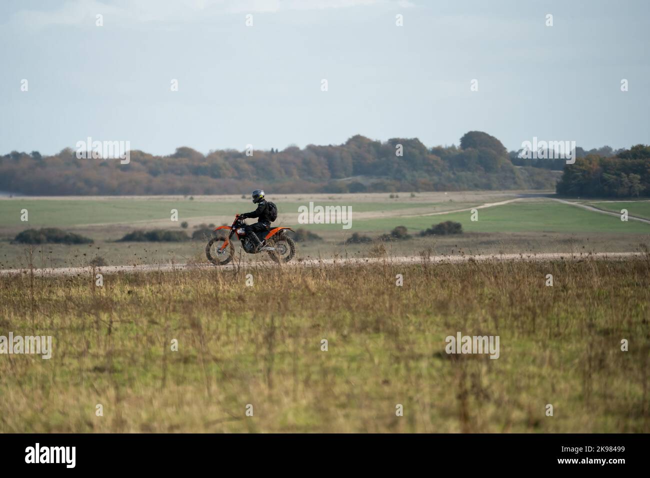 a motor cyclist (biker) riding their off-road motorbike along a dusty ...