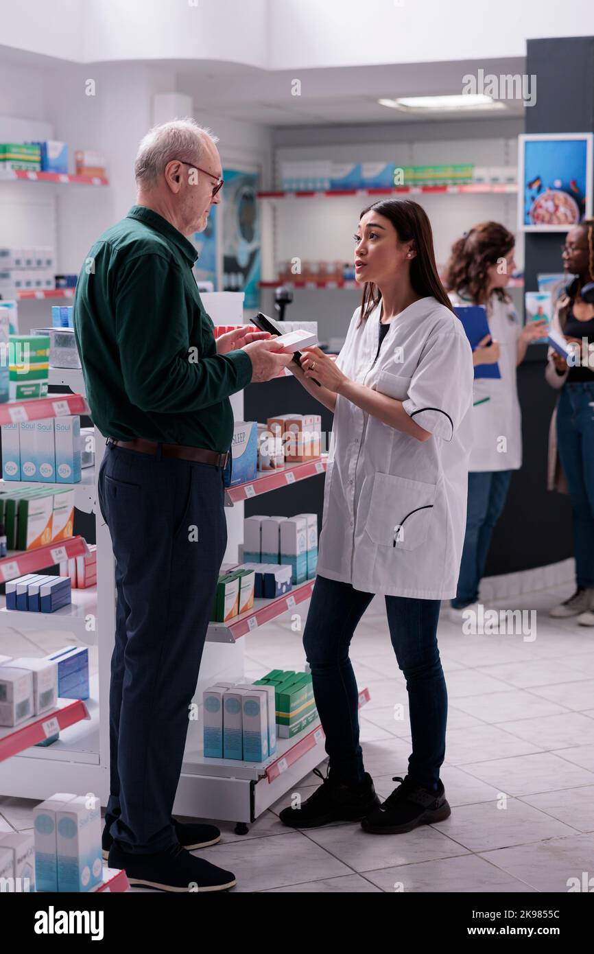 Helpful pharmacist offering medical advice to senior client during ...