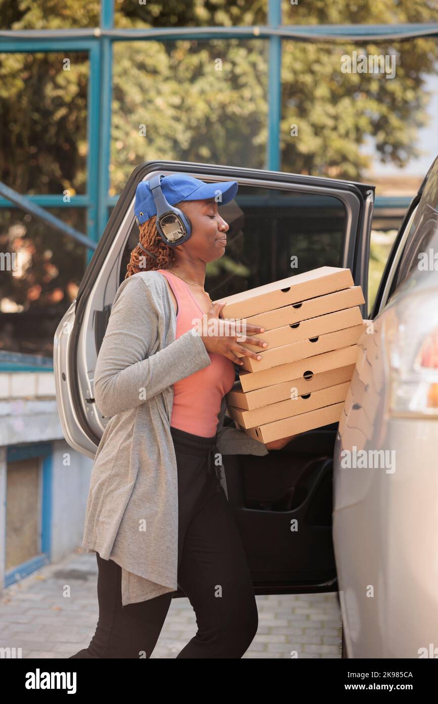 Pizzeria courier delivering pizza to office by car, side view. Lunch ...