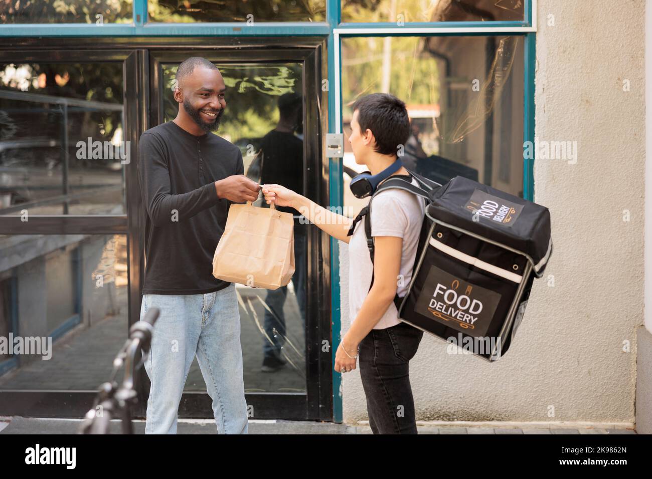 Food delivery service, young woman courier giving client lunch paper ...