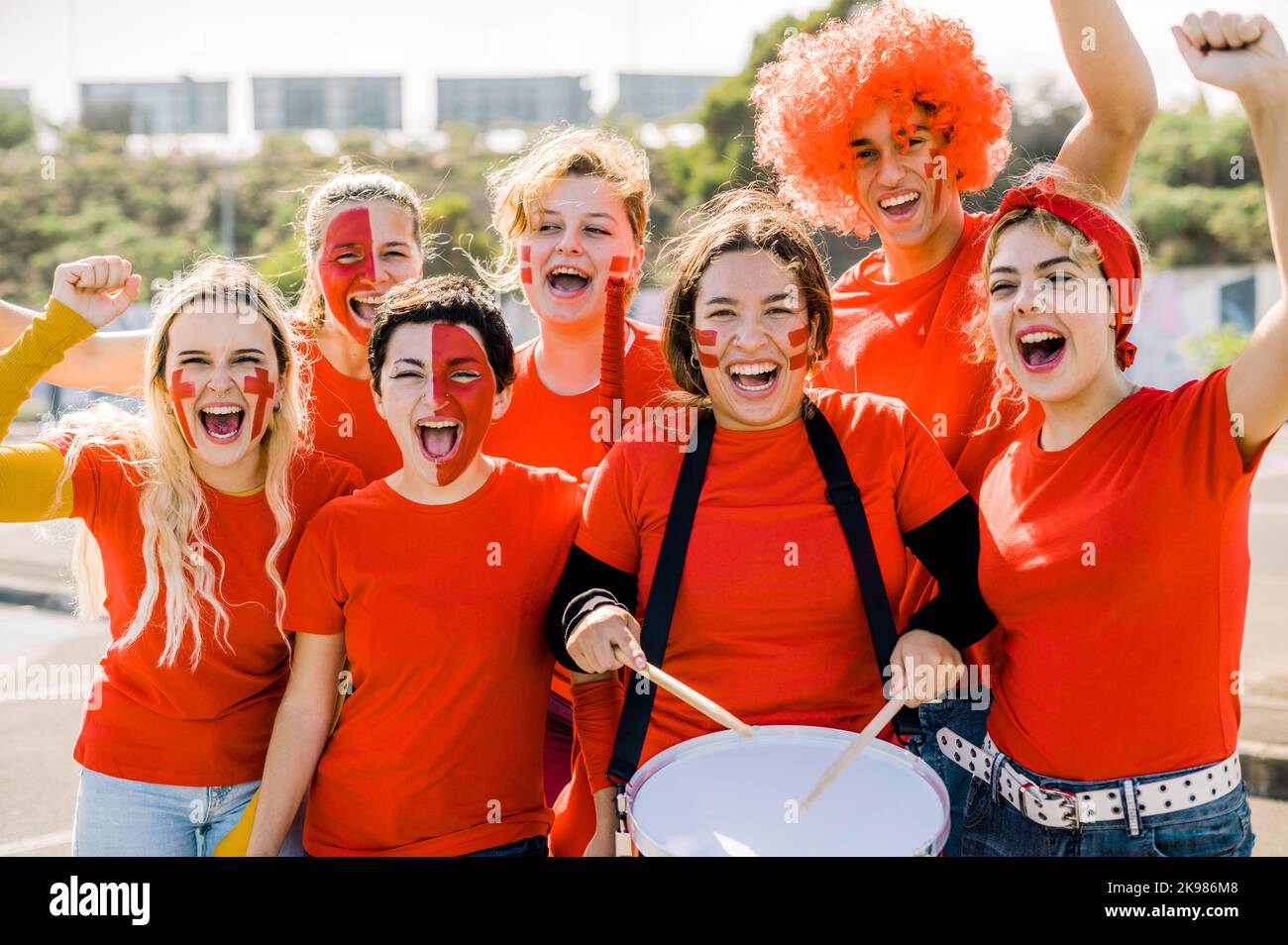 Group of young sports fans in red jerseys have fun and cheer on their ...