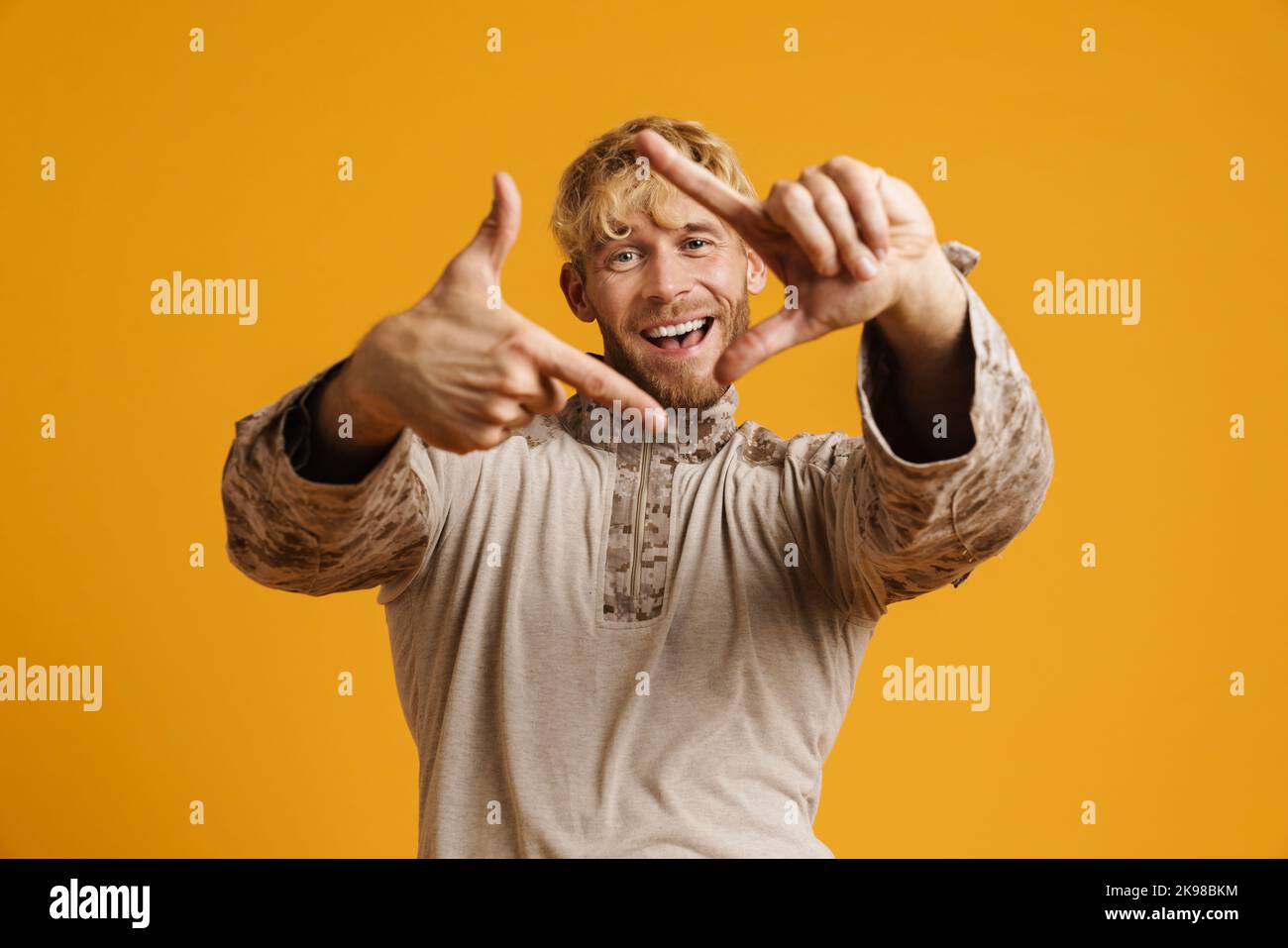 European military man wearing uniform smiling and making frame gesture ...