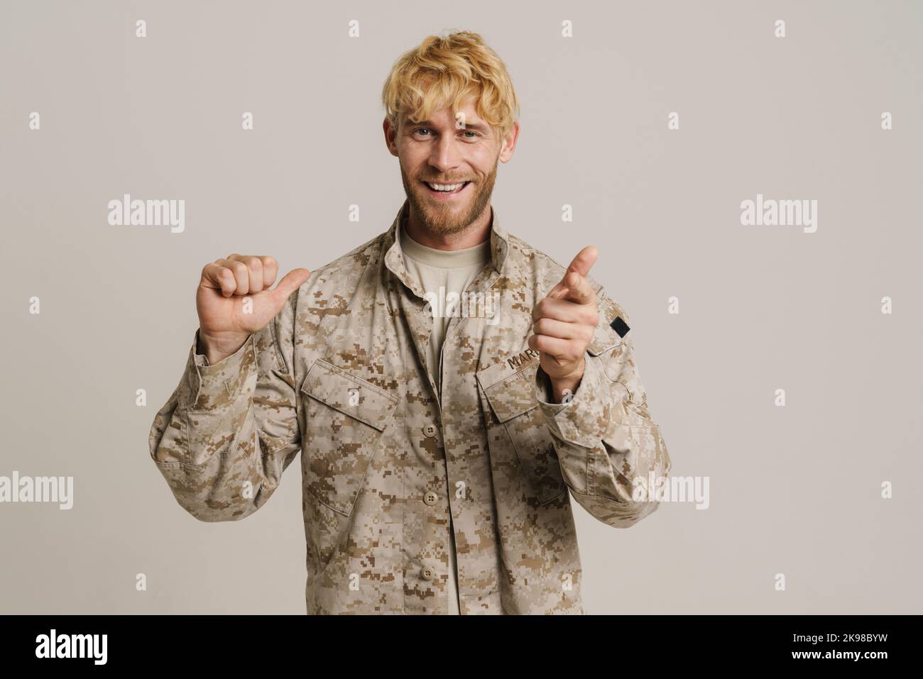 White military man wearing uniform smiling and pointing fingers away ...
