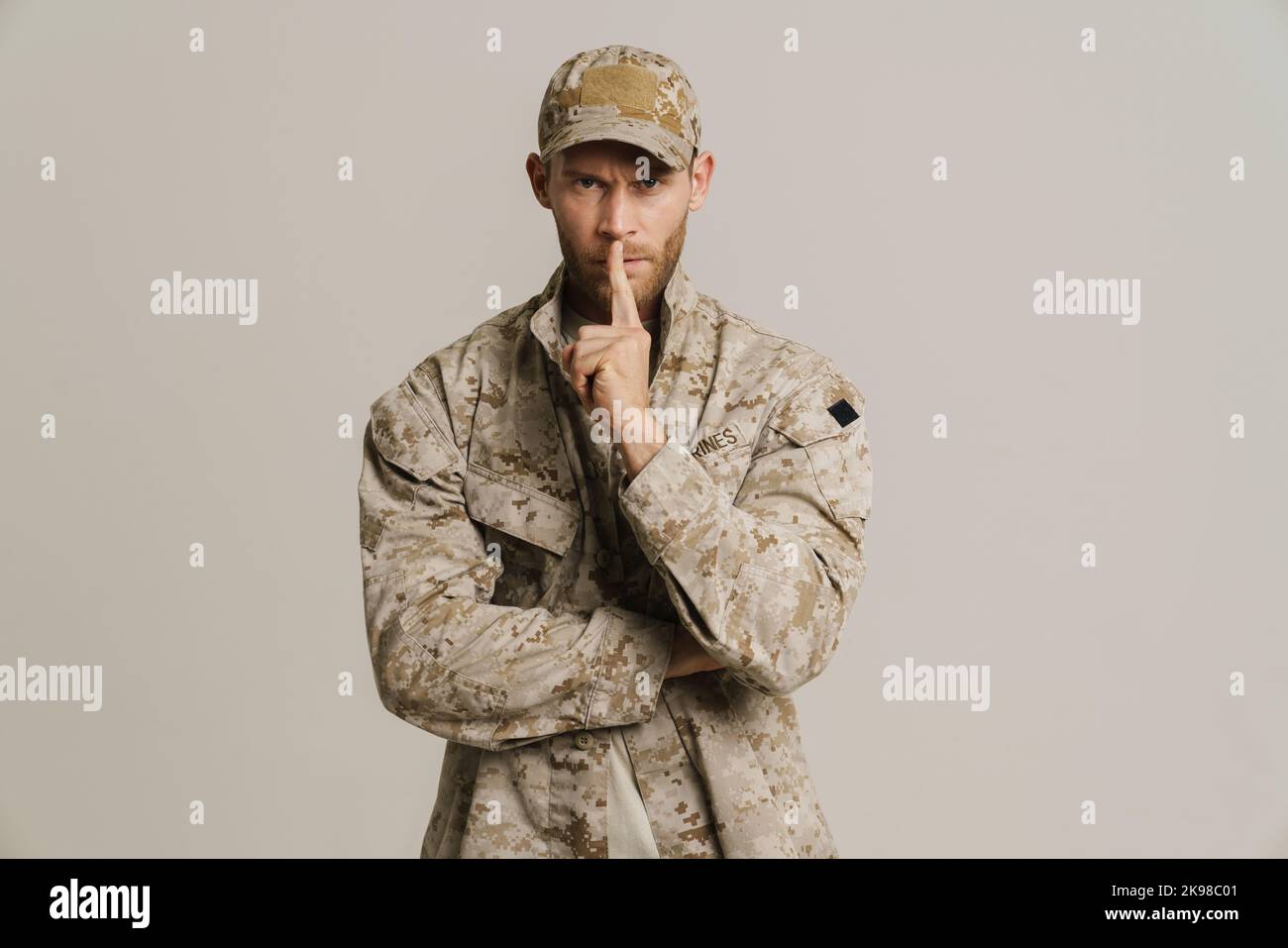 White military man wearing uniform making silence gesture isolated over ...