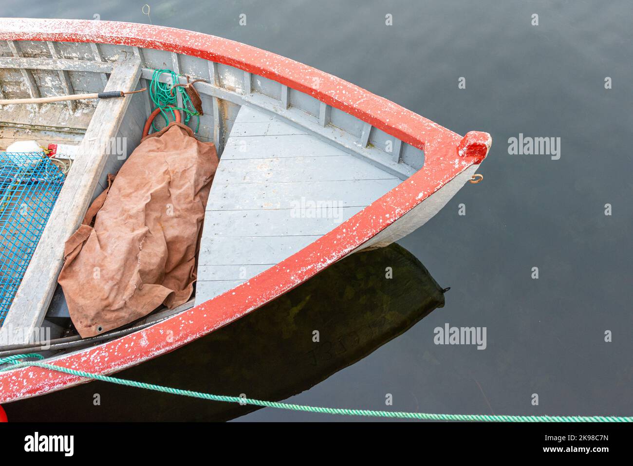 A grey wooden boat, a fishing boat, with red trim. The motorboat is ...