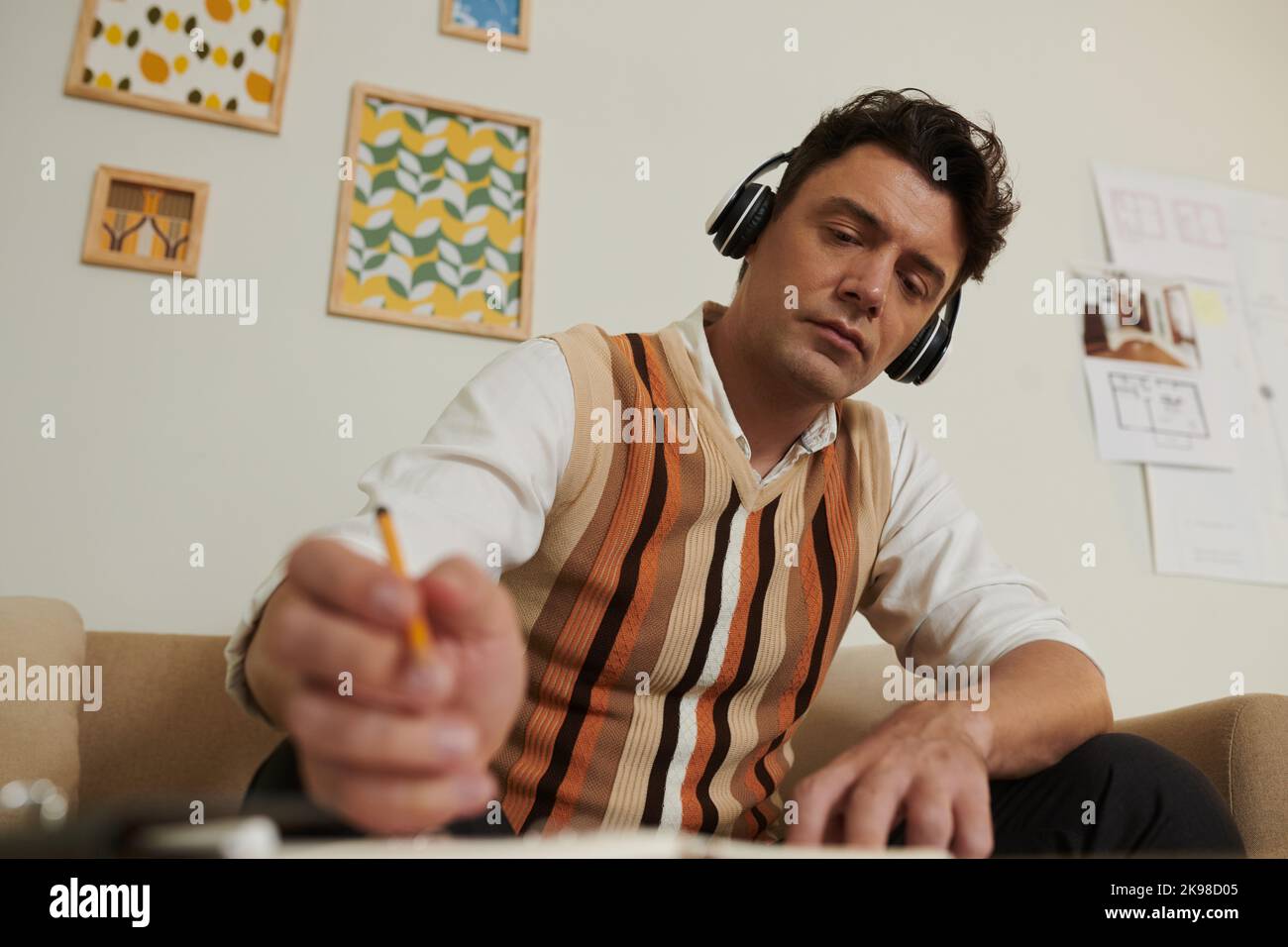 Creative architect listening to music in headphones when drawing house ...