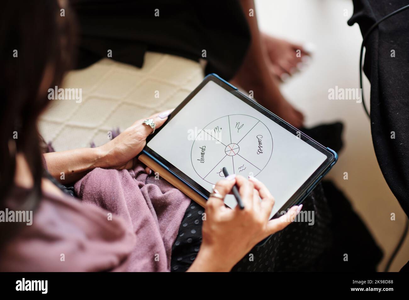 Close-up image of astrologer drawing natal card on tablet computer ...