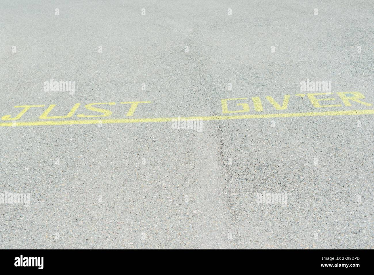 Just Giv'er wrote in yellow ink on the pavement of a road. The letters ...