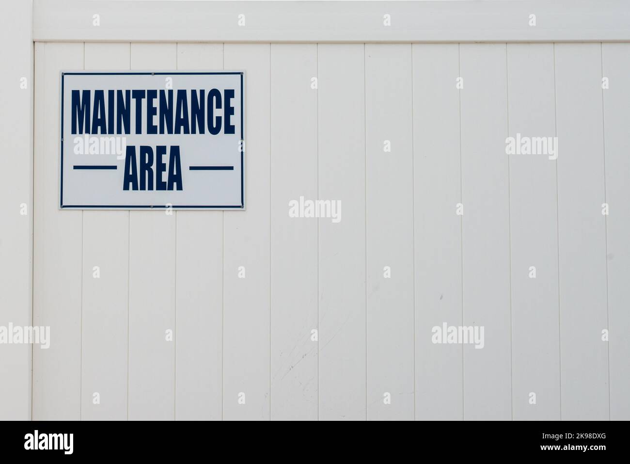 A white wooden fence with a small sign in the left corner. The sign is ...