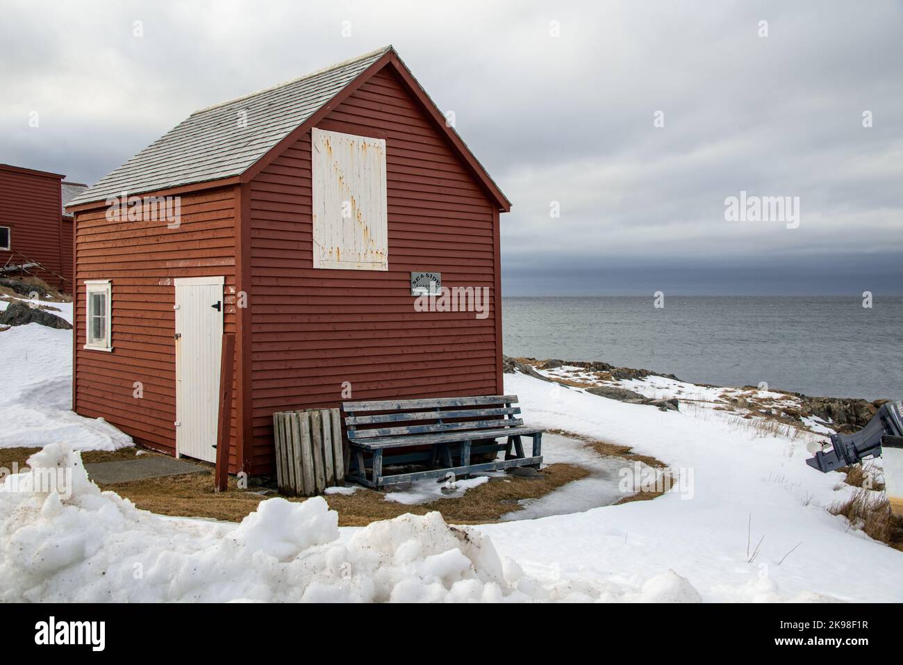 A small rustic red colored barn or shed with a white single wooden door ...