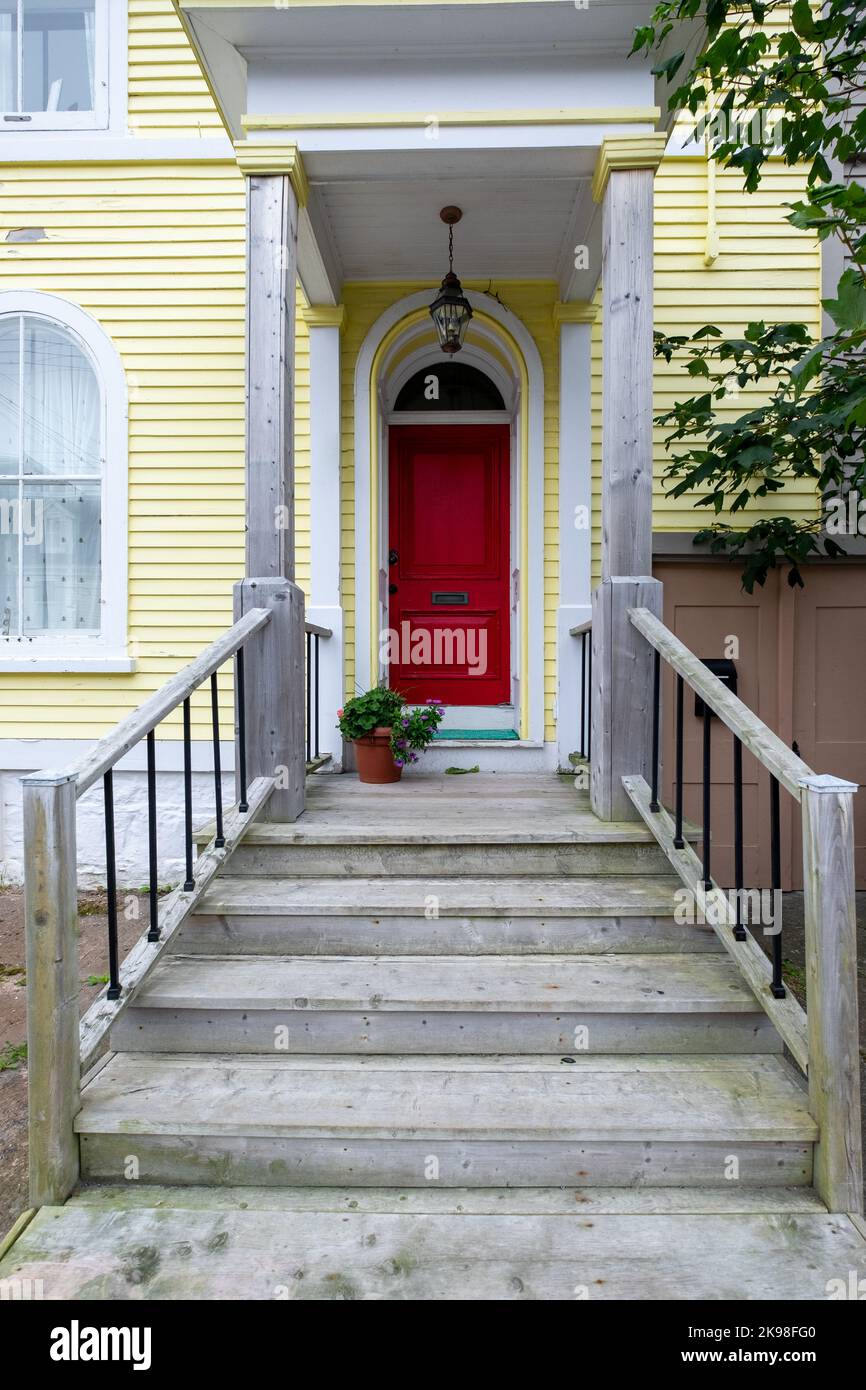 The exterior of a bright yellow house with white trim. There are ...