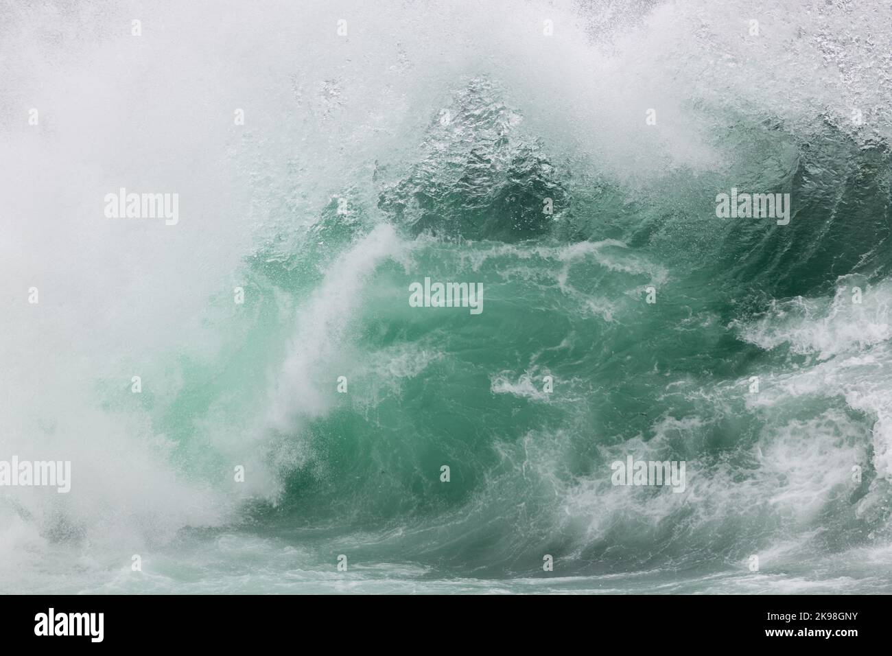 An angry teal green color massive rip curl of a wave as its barrel ...