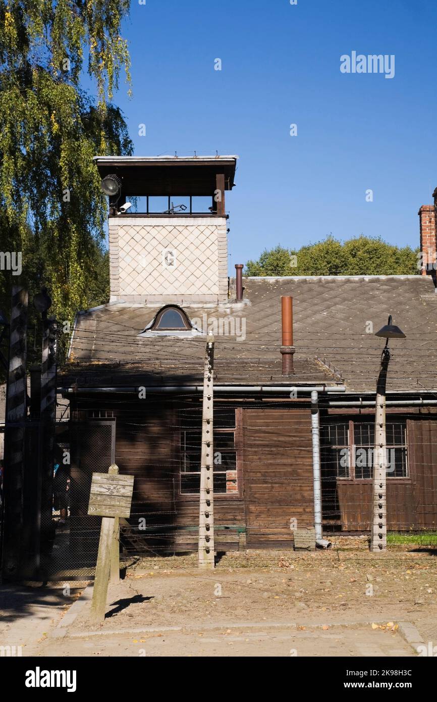 Barb wire fence and building with a guard tower inside the Auschwitz I ...