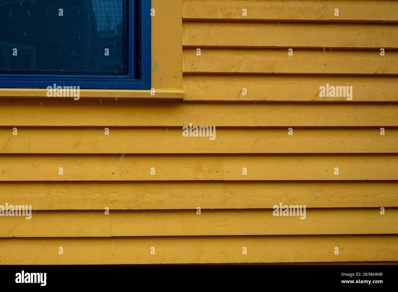 The exterior of a bright yellow narrow wooden horizontal clapboard wall ...