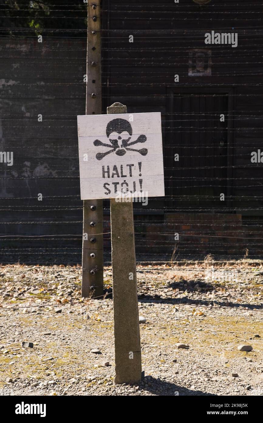 Stop warning sign and electrified barbwire fence inside the Auschwitz I ...