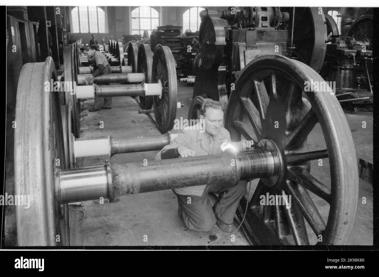 Workshop workers control the turning on the wheel axle Stock Photo - Alamy