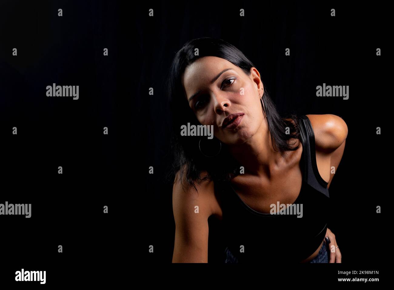 Studio portrait of young woman looking at camera against simple studio ...