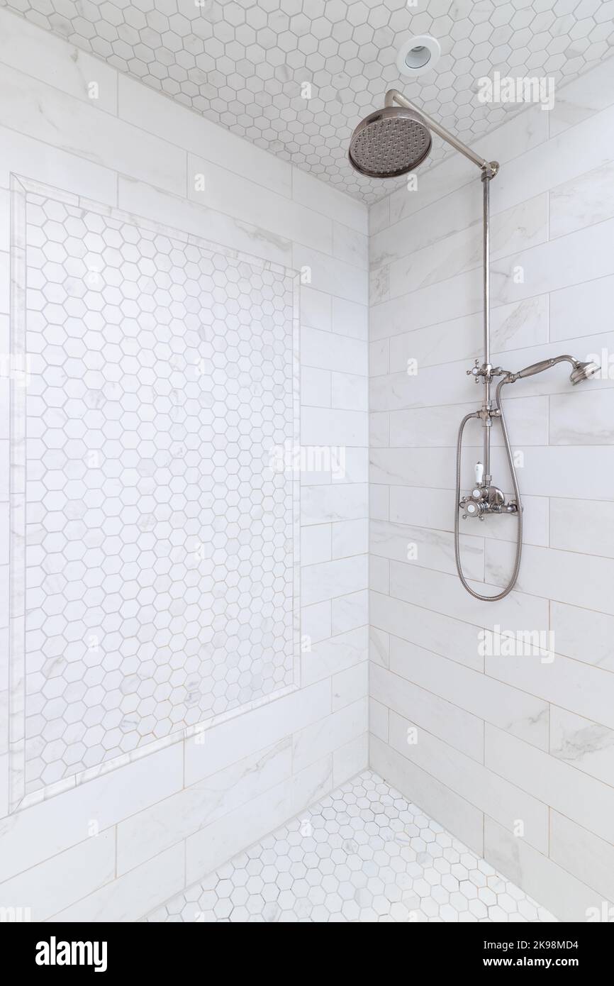 A walk-in shower in a luxury bathroom with hexagon and subway tiles and ...