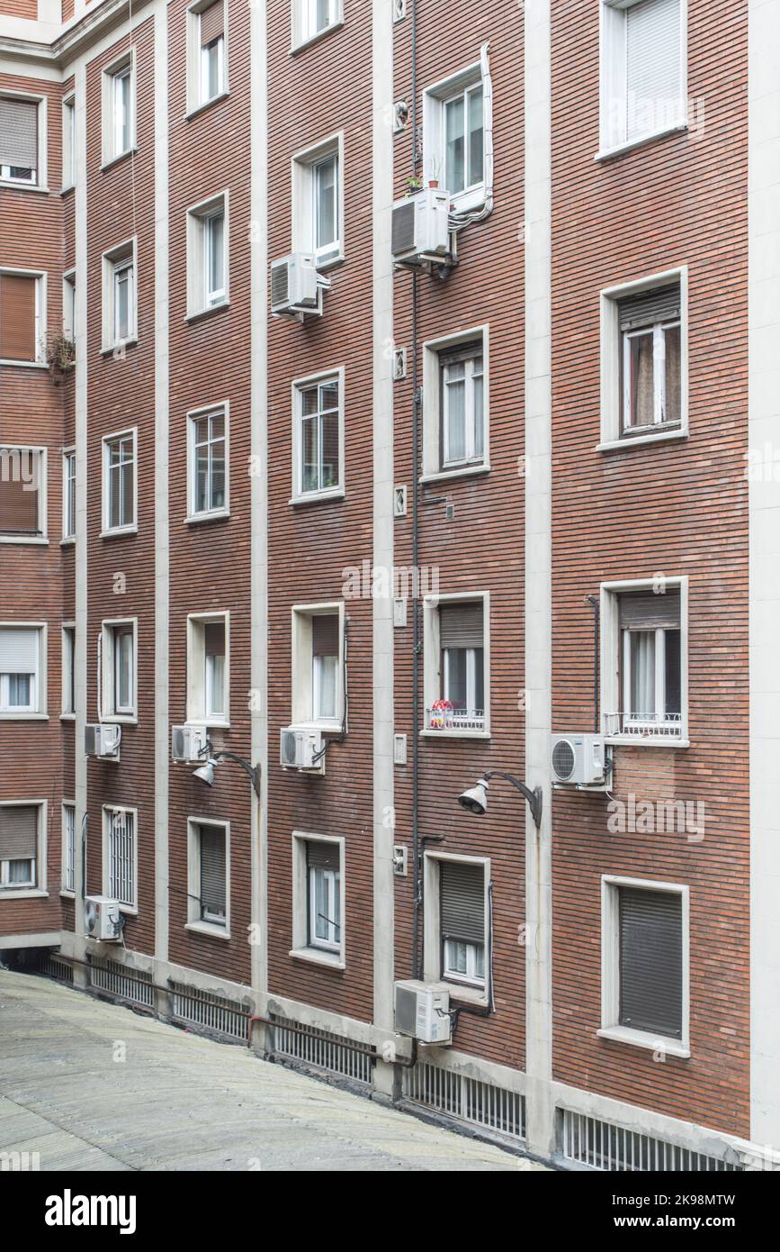 Facade of a building with exposed clay-colored brick, windows with air ...
