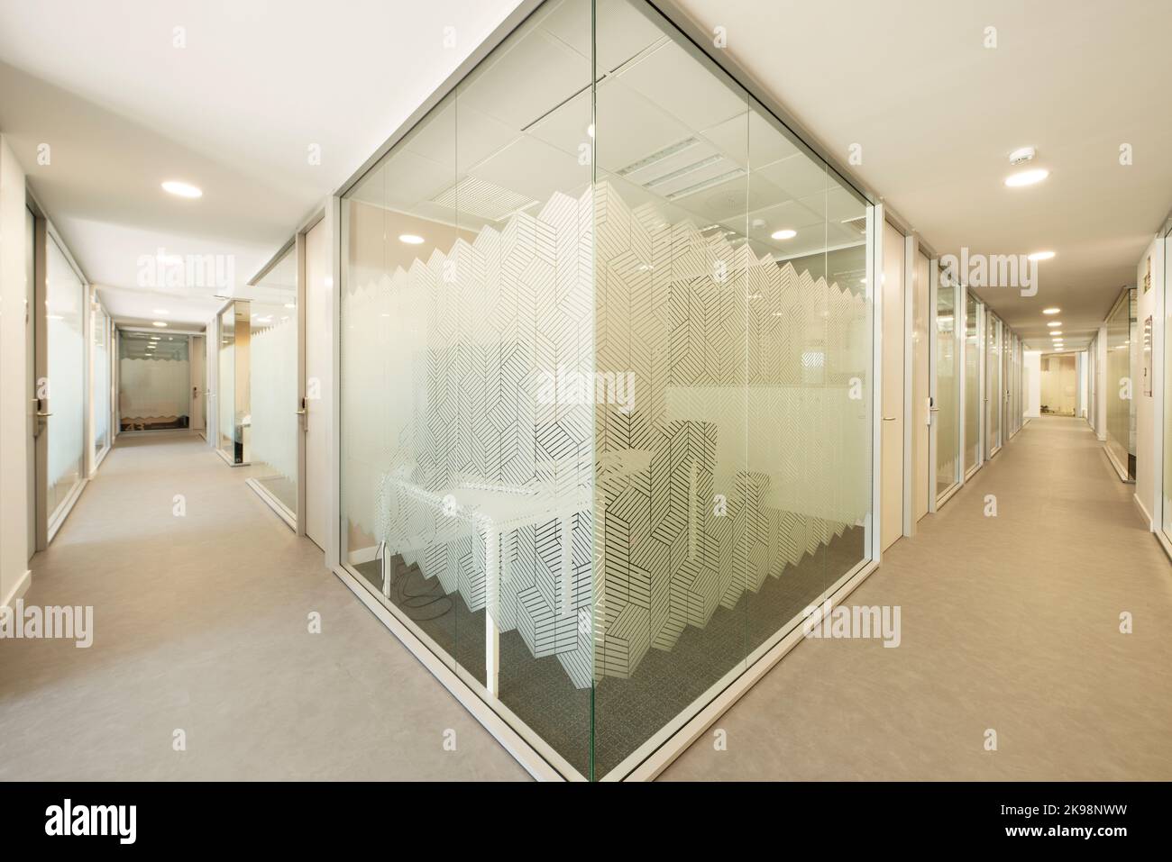 Corridor of a coworking office floor with cubicles separated by glass ...