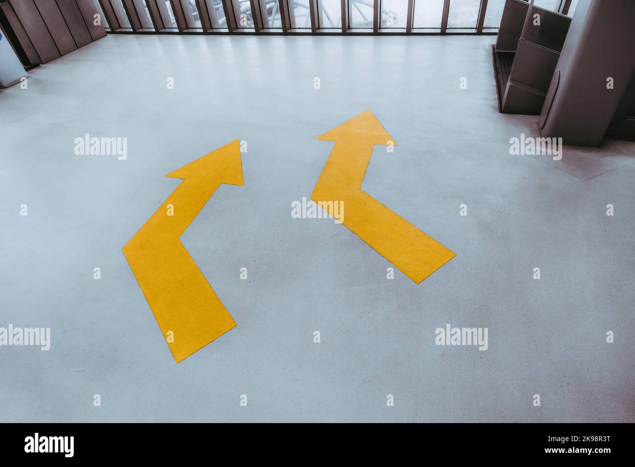 Two indoor yellow stickers in the shapes of broken arrows as a way ...