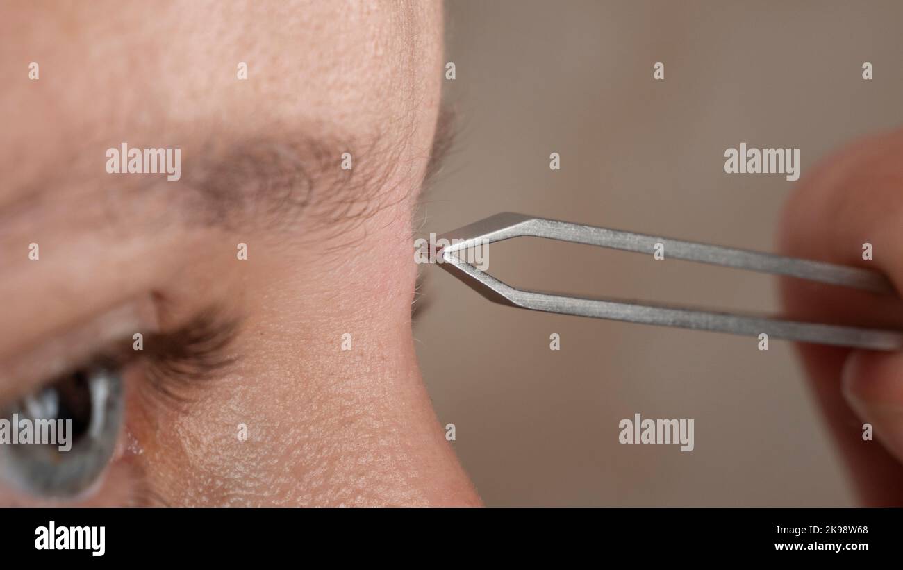 woman plucking eyebrows with tweezers closeup Stock Photo - Alamy