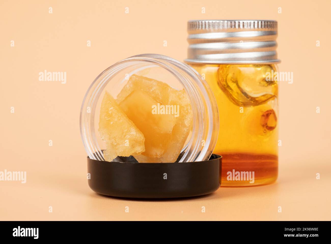 glass jar with brown cannabis wax, pieces of hardened resin of ...