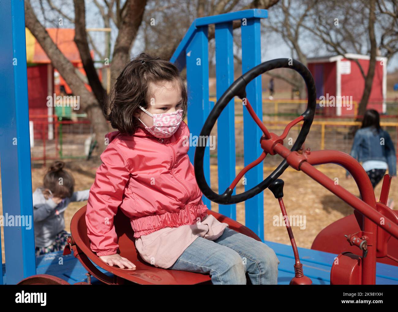 little girl wearing a mask pretending to drive the tractor exhibit at ...