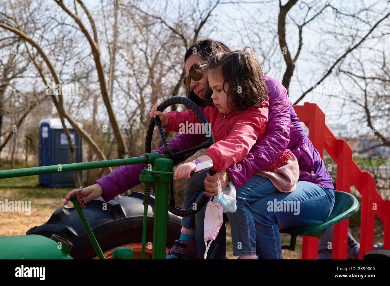 Mom and daughter pretending to drive a tractor at an exhibition farm ...