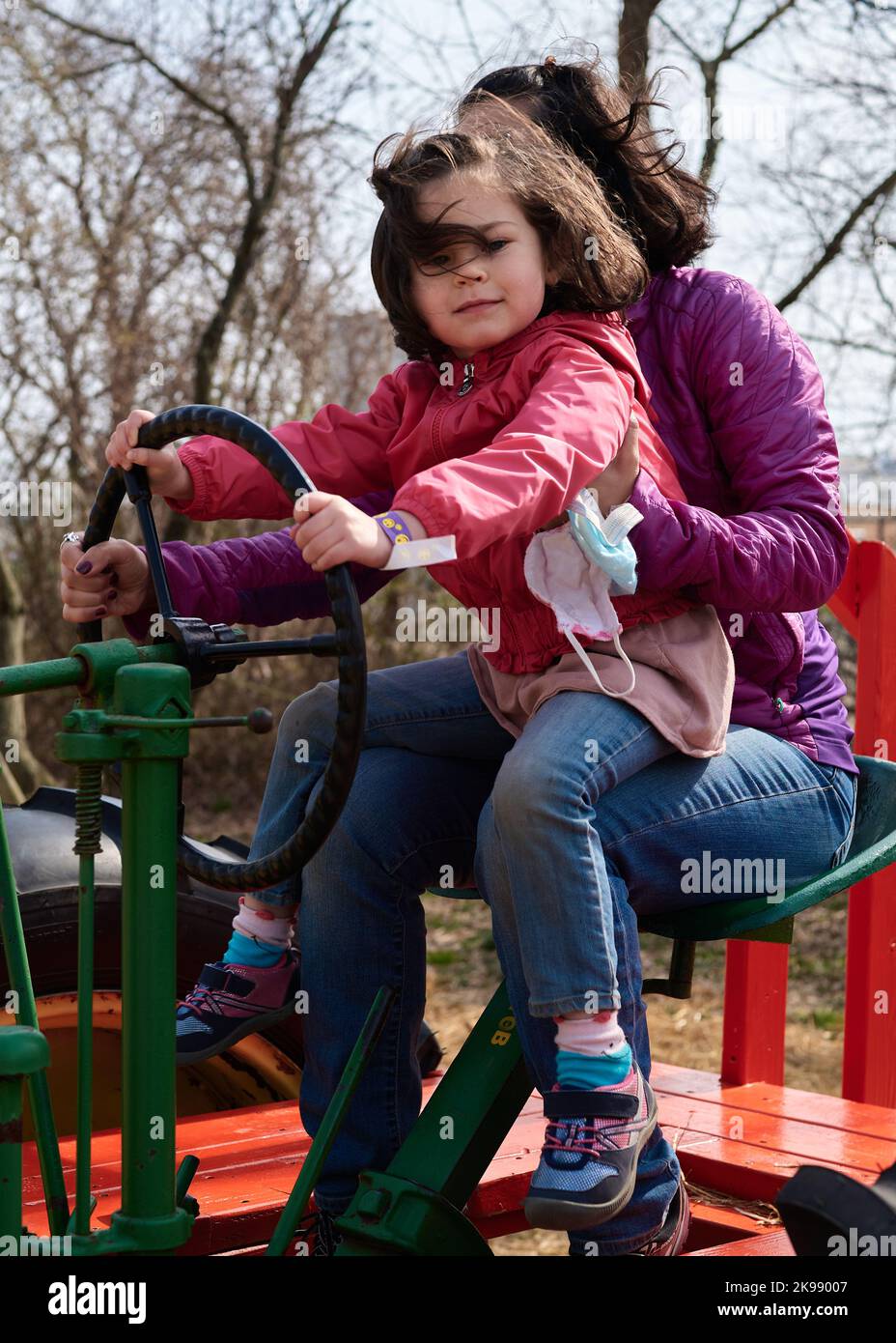 Mom and daughter pretending to drive a tractor at an exhibition farm ...