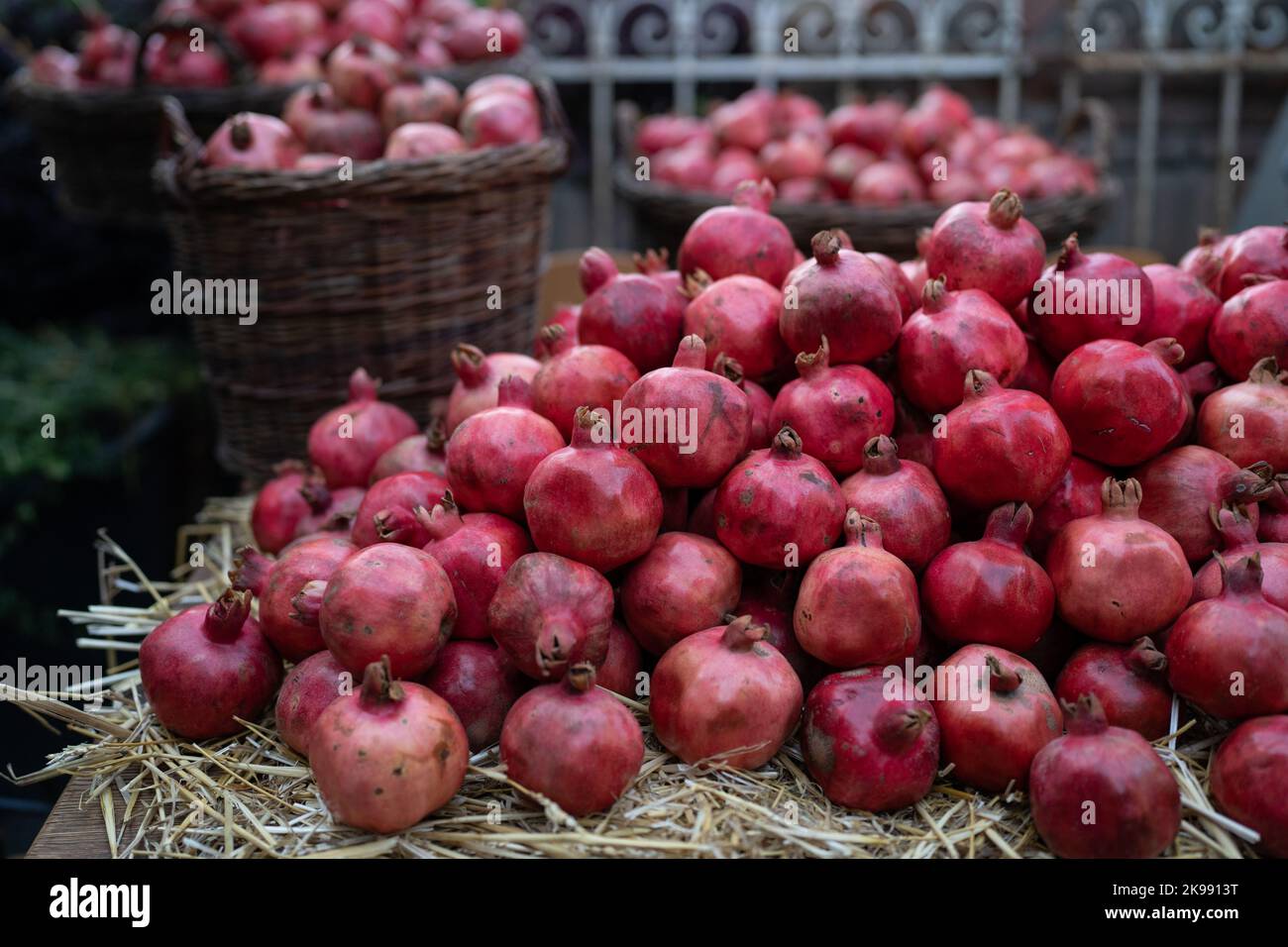 Harvest of ripe pomegranate on dry straw at outdoor farmer market in ...