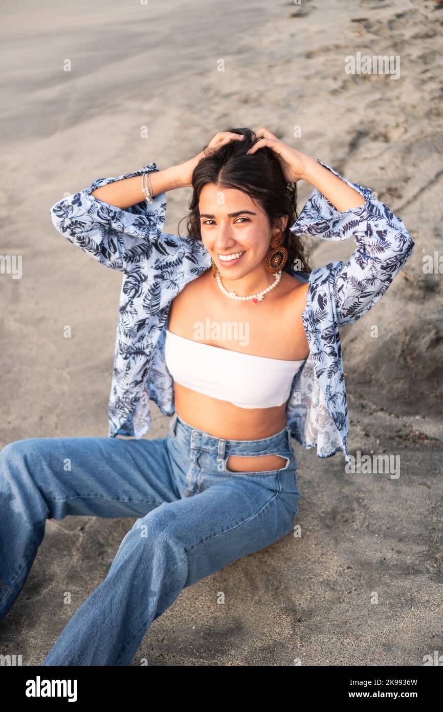 woman in casual clothes sitting on the shore of the beach posing in ...